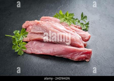 Raw suckling pig fillet offered on a black slate slab as closeup Stock ...
