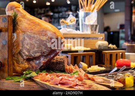 A LEG OF PARMA HAM ON A WOODEN AND SILVER HAM STAND WITH A SLICE CUT ...