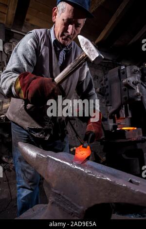blacksmith manually forging the red hot molten metal on the anvil in ...
