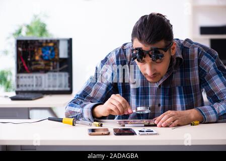 Handsome young man with magnifier and mobile phone on pink background ...