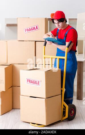 The young male contractor with boxes working indoors Stock Photo - Alamy