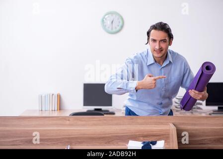 The young handsome businessman doing exercises at workplace Stock Photo ...