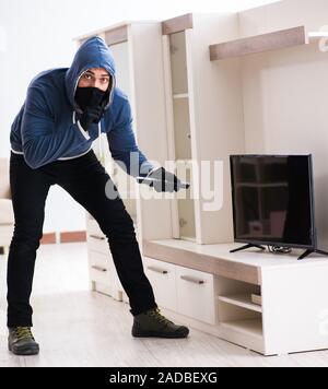 Man burglar stealing tv set from house Stock Photo - Alamy