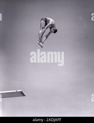 Young black swimmer doing exercise while working out isolated over blue ...