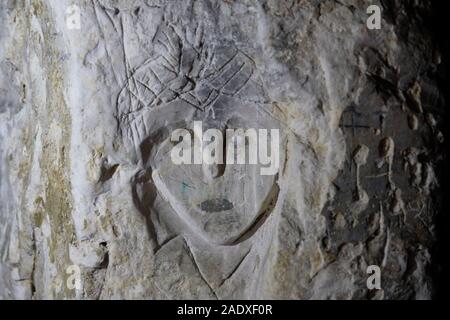 A face carved into the rock in the Cité souterraine de Naours ...