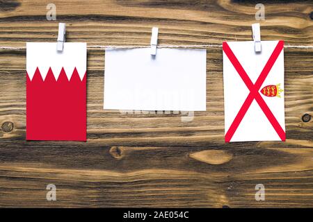 Hanging flags of Bahrain and Guernsey attached to rope with clothes ...