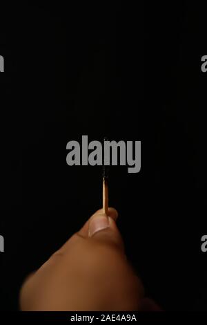 Hand holding an extinguished matchstick on black backgrounds Stock ...