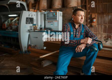 Woodworker in uniform at his workplace on lumbermill, woodworking ...