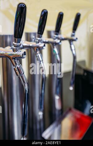 Row of shiny chrome beer taps with black handles, hanging from long ...