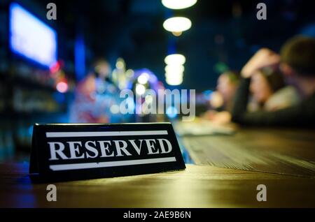Reserved sign standing on wooden table in bar. Pub interior background ...