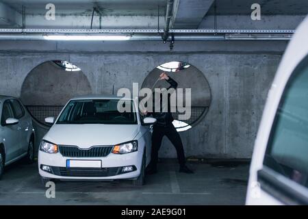 Masked man is robbing a car with wrecking bar Stock Photo - Alamy