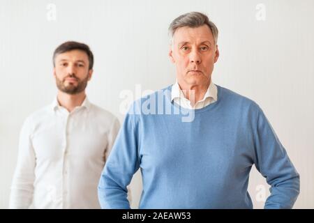 Mature Son Standing Overshadowed By His Elderly Father, White ...
