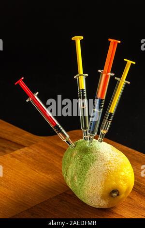 Moldy lemon with syringe. Chemistry in food. Unhealthy food. Decayed ...