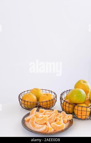 Beautiful peeled tangerines in a plate and metal basket isolated on ...