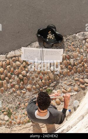 Busker playing music on her flute in doorway for money Stock Photo - Alamy