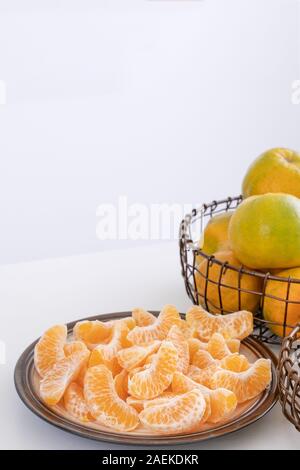 Beautiful peeled tangerines in a plate and metal basket isolated on ...