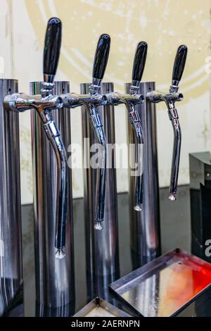 Row of shiny chrome beer taps with black handles, positioned above ...
