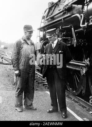 Engineer standing by steam train Stock Photo - Alamy