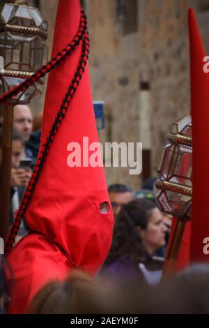 Portrait of a Nazarene in a red hood and white robe holding a candle ...