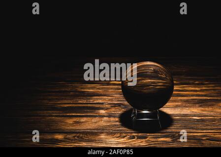 Crystal ball on wooden table with defocused bottle and filled glass in ...