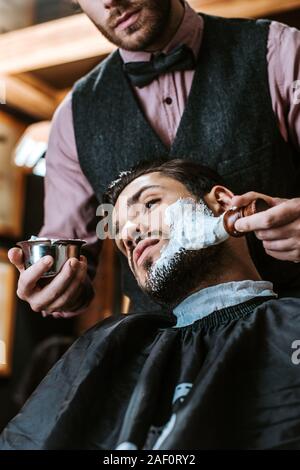 low angle view of bearded barber doing haircut to teenage client in ...
