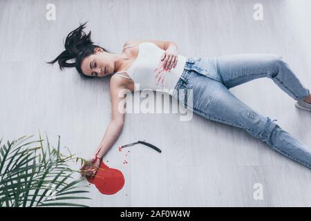 overhead view of lifeless woman with cut bleeding veins lying on floor ...