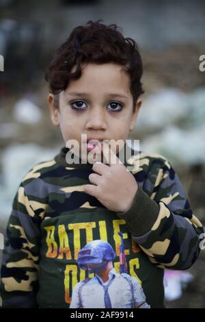 A Palestinian child looks at the camera in front of his house in a poor ...