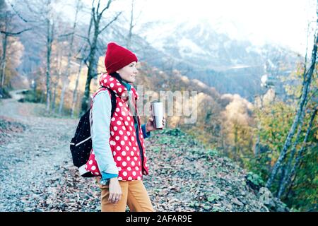 Thermos with coffee in hand. Landscape with snow-covered ridge of Altai ...