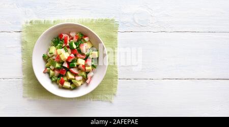 Salad from avocado, radish, cucumber, greens in bowl over light wooden ...