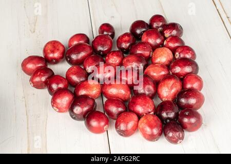 Lot of whole fresh red cranberry on round bamboo coaster on grey stone ...