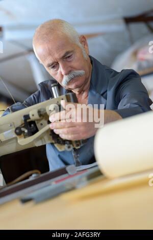 Senior man employee sewing, stitch clothes, guy work with mannequin ...