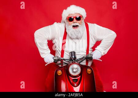 Portrait of attractive cheery Santa riding car carrying giftboxes ...