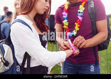 Close Up Of Friends At Entrance To Music Festival Putting On Security ...