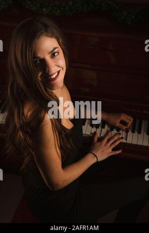 Positive young female singer in casual clothes with microphone in light ...