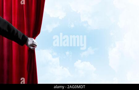 Cloudy landscape behind red curtain and hand holding it Stock Photo - Alamy