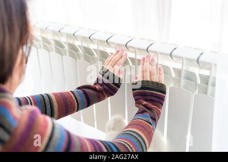 Girl warms up the frozen hands above hot radiator, close up view Stock ...