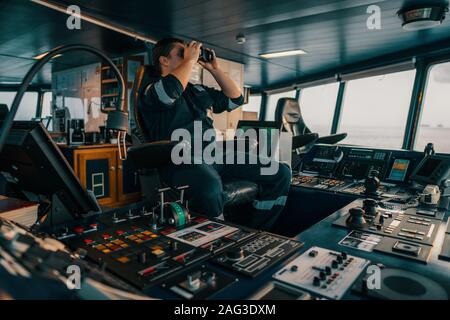 Captain on ship looking through a telescope Stock Photo - Alamy