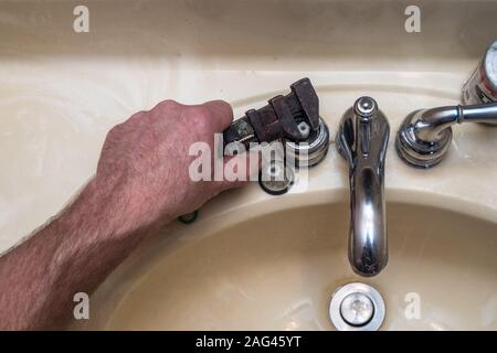 plumber working on a broken tap in the kitchen Stock Photo - Alamy