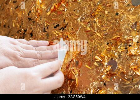 hand of buddhist gilding gold leaflet on golden ball in temple to ...