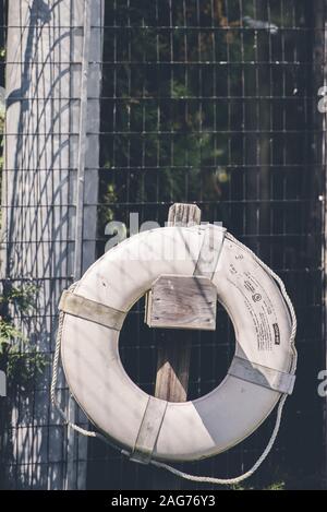 A vertical shot of an orange life saver hanging on a wooden pole on the ...