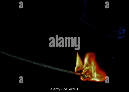 Closeup shot of a burning match softly dancing on a black background ...