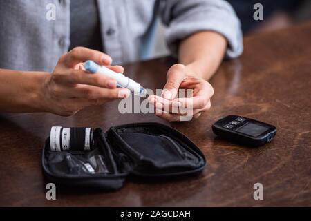 Cropped woman hands holding lancet pen to prick finger to check sugar ...