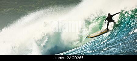 A surfer is enjoying the strong waves on the beach with his surfboard ...