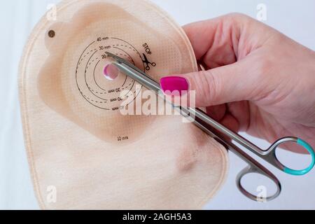 Top view on ostomy bag and scissors in female hand on white background ...