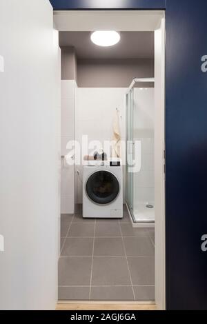 Modern style bathroom with washing machine and dryer combo. Vertical ...