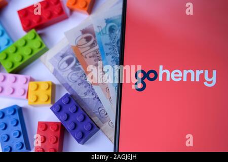 GoHenry logo on the smartphone screen and some banknotes and lego parts ...