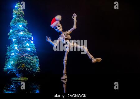 A skeleton dancing around a Christmas Tree with lights Stock Photo - Alamy