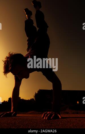 Acrobatic man balancing during a handstand on the concrete floor of the ...