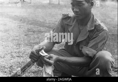 [a KNIL soldier holds the head of a snake while a lieutenant watches ...