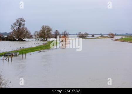 Earith, UK. 22nd Dec, 2019. A woman walks through a flooded road as the ...
